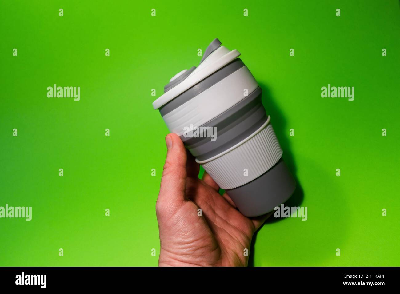 Reusable silicone cup for coffee in hand on a green background Stock ...
