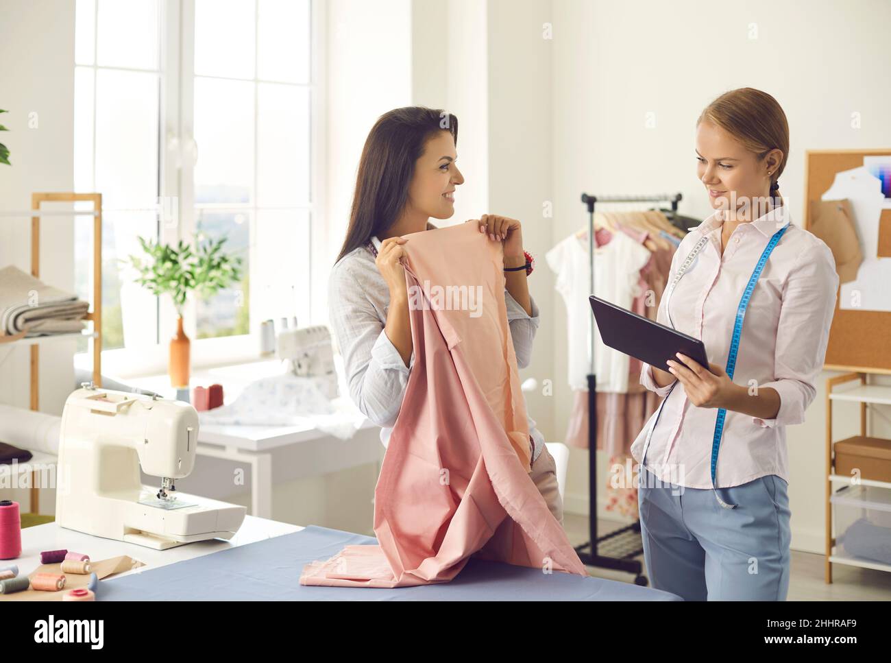 Smiling female dressmakers create new clothing pieces in atelier Stock ...