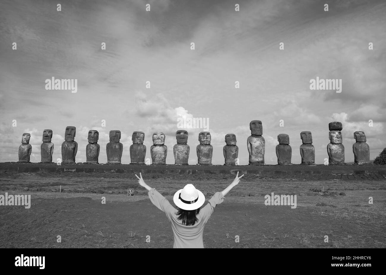 Monochrome image of a happy female visitor in front of the huge Moai ...