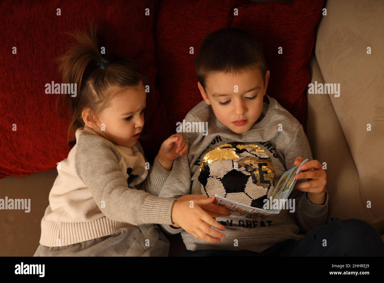 Two kids boy and girl reading together at home on the couch Stock Photo ...