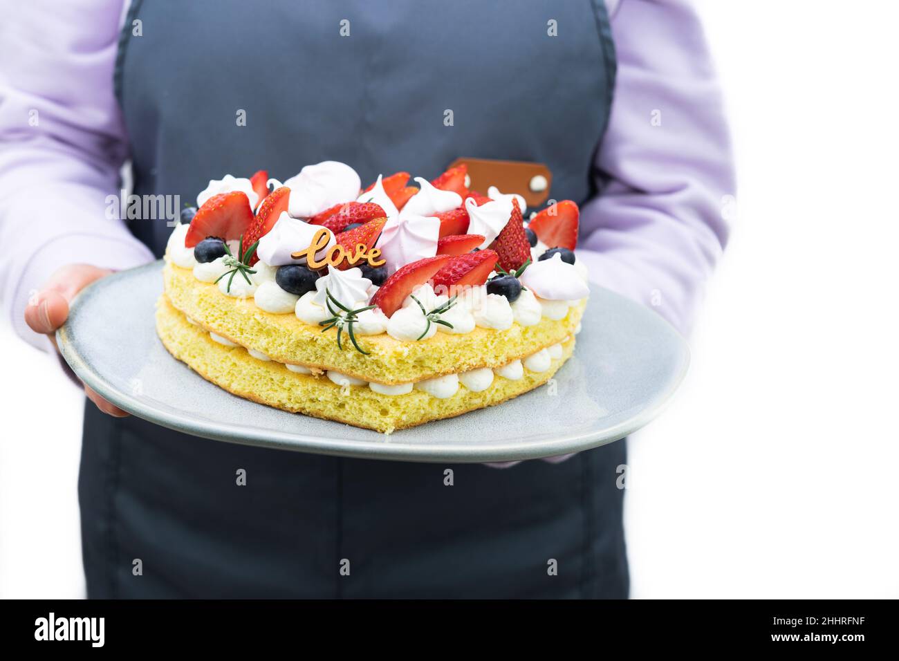 Woman waitress with heart-shaped cake decorated with red fruits and ...