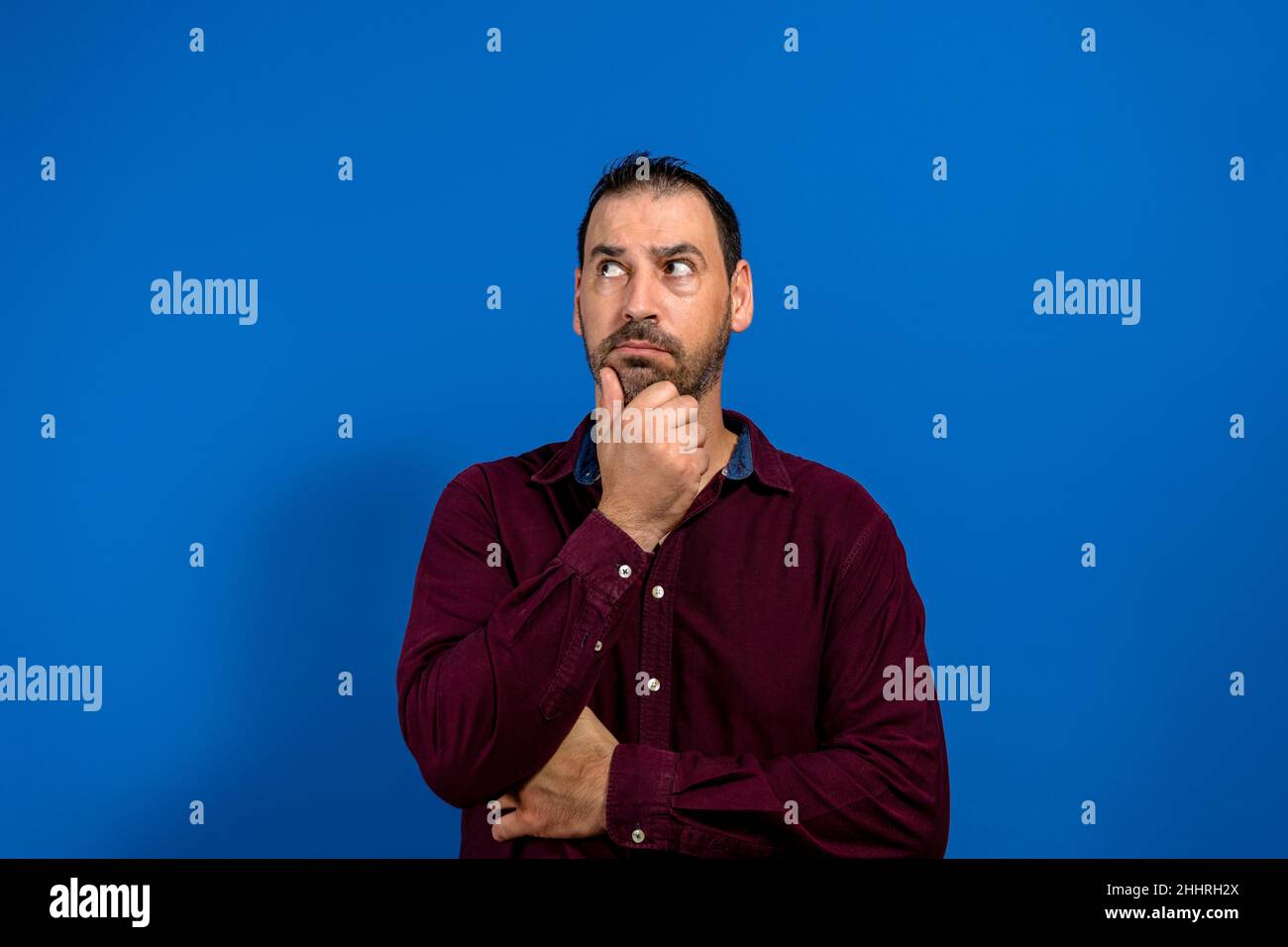 Thinking man isolated on blue background. Closeup portrait of a casual ...