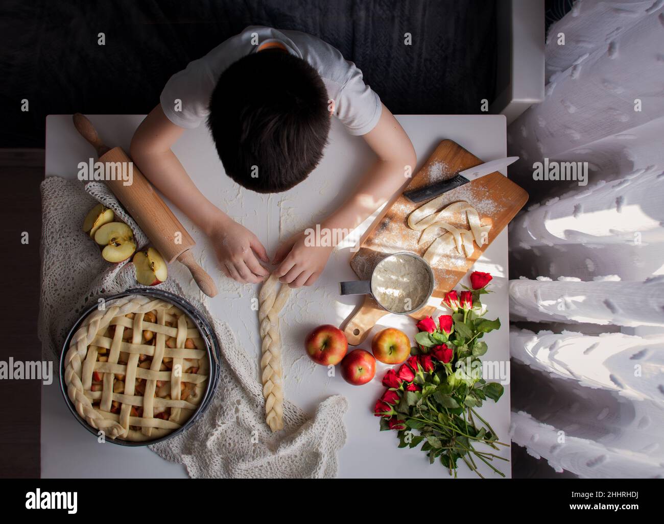 Cooking apple pie. The boy is kneading raw dough to make a pie. The ...
