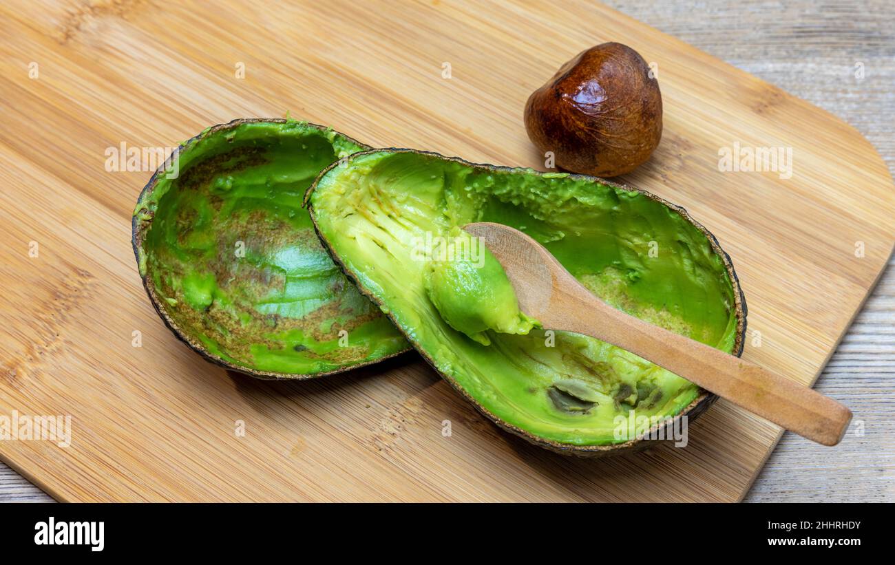 avocado cut and emptied of pulp with wooden spoon on bamboo cutting ...