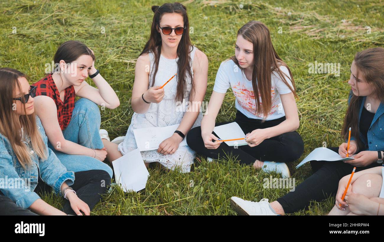 A group of female students are sitting in a circle on a meadow for ...