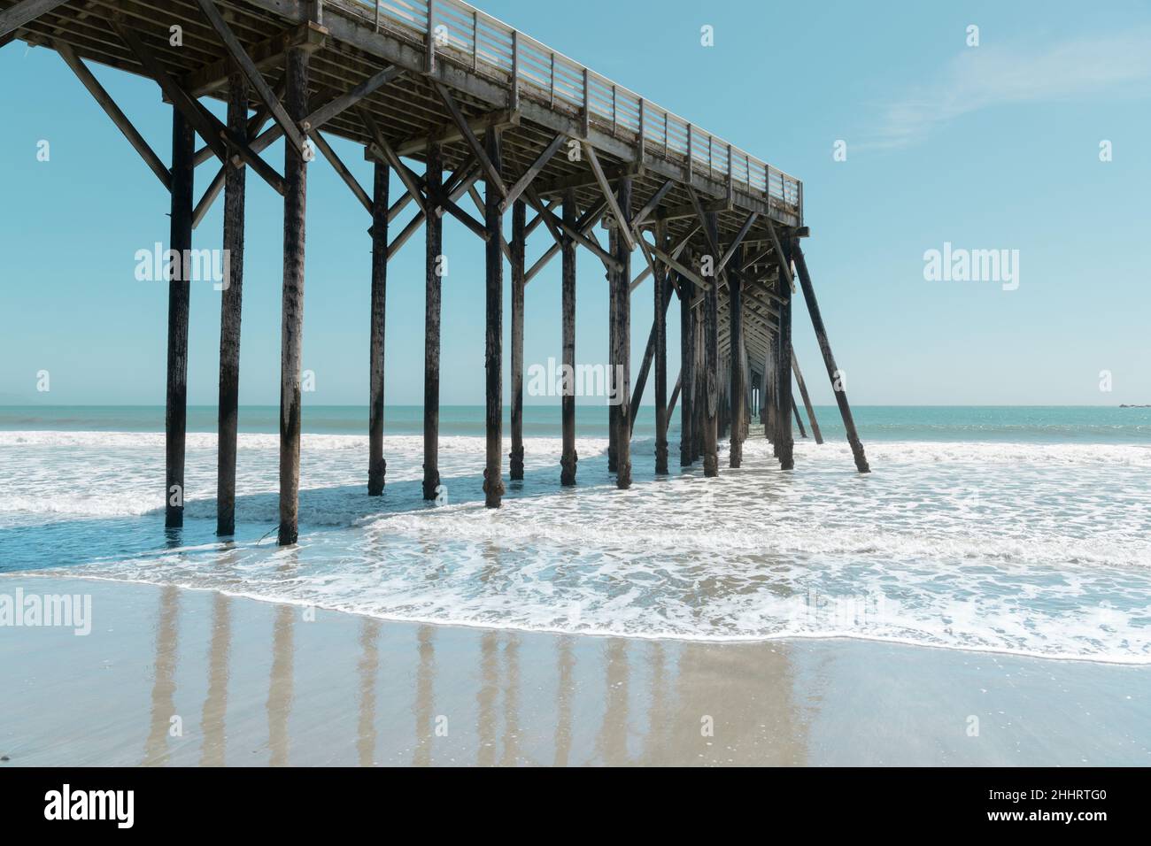 Pier projecting from a wet, sandy beach into the Pacific Ocean in San ...