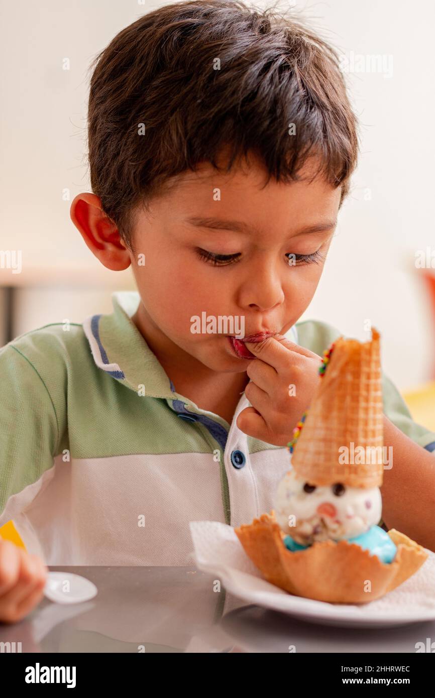 Latin boy eating a delicious snowman shaped ice cream cone Stock Photo ...