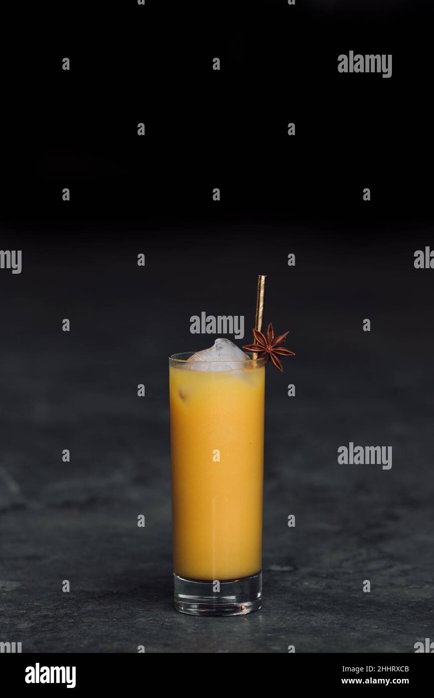 yellow turmeric thai iced tea with star anise and gold drinking straw ...