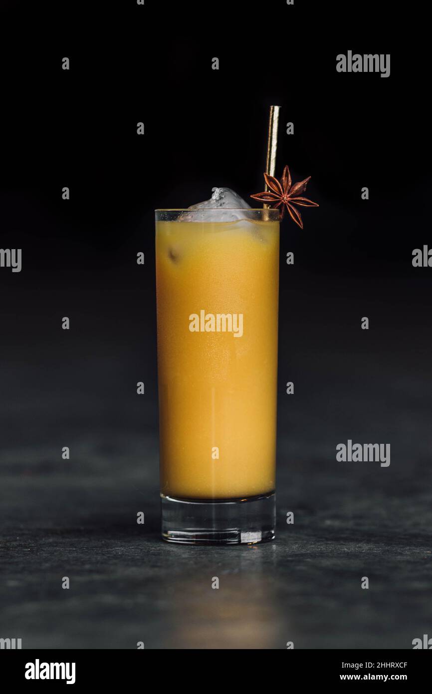 yellow turmeric thai iced tea with star anise and gold drinking straw ...