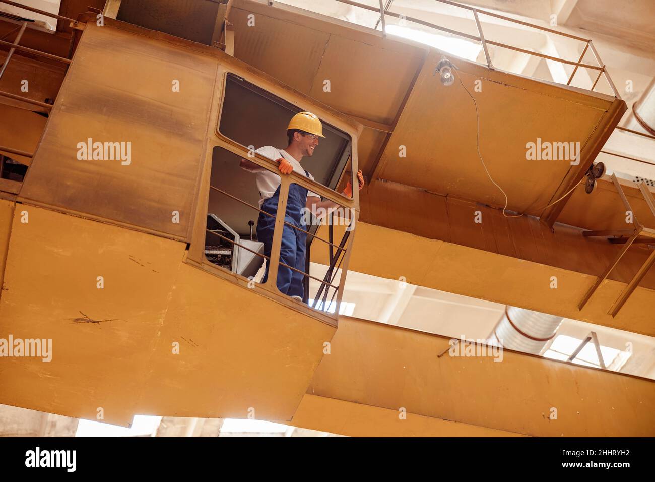 Cheerful builder standing in operator cabin of overhead crane Stock ...