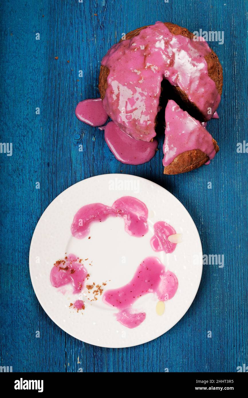 Homemade chocolate cake with violet sugar icing and dirty plate on blue ...