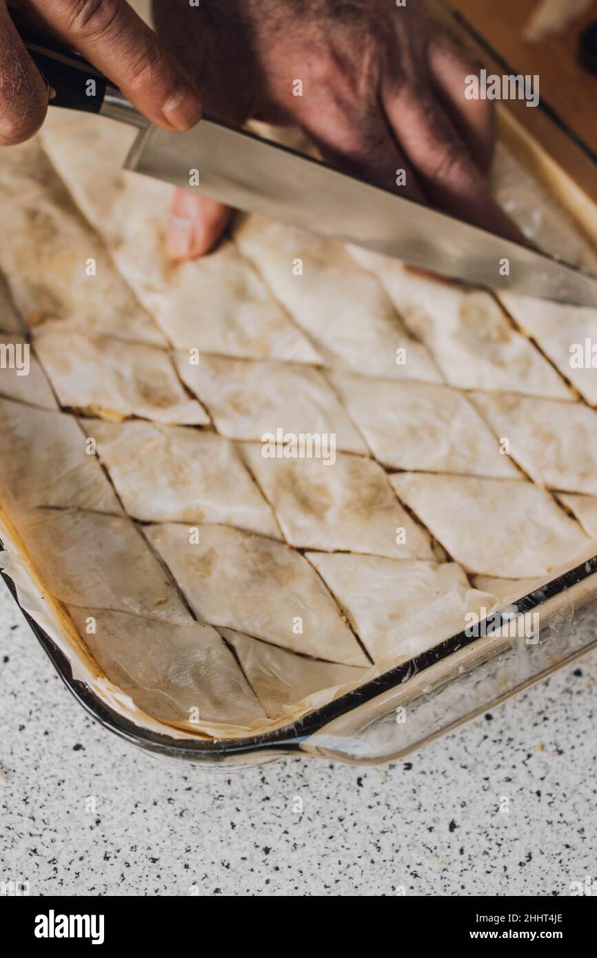 male hand cutting baklava dessert into diamond shapes Stock Photo - Alamy