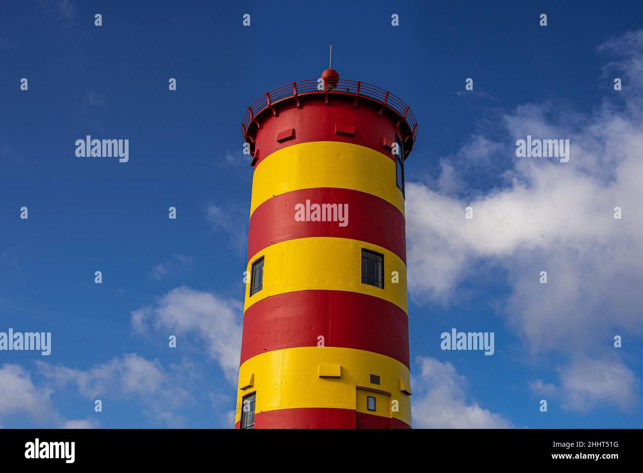 The yellow-red lighthouse of Pilsum with a blue cloudy sky Stock Photo ...