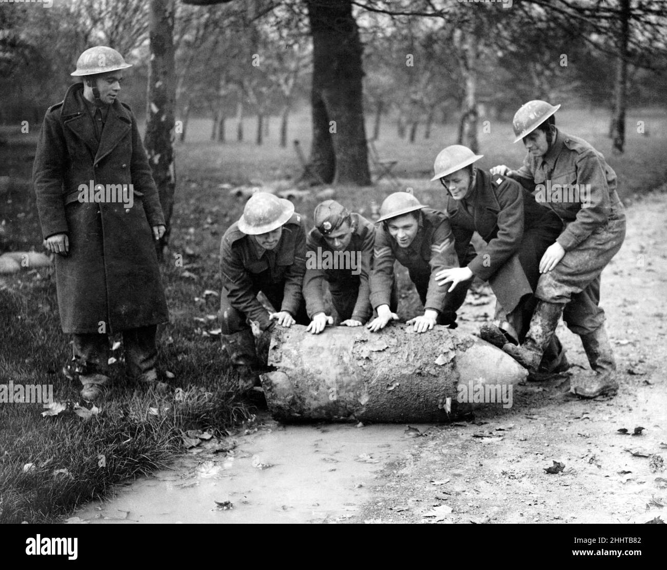 Members of a army bomb disposal squad rolling a unexploded German bomb ...