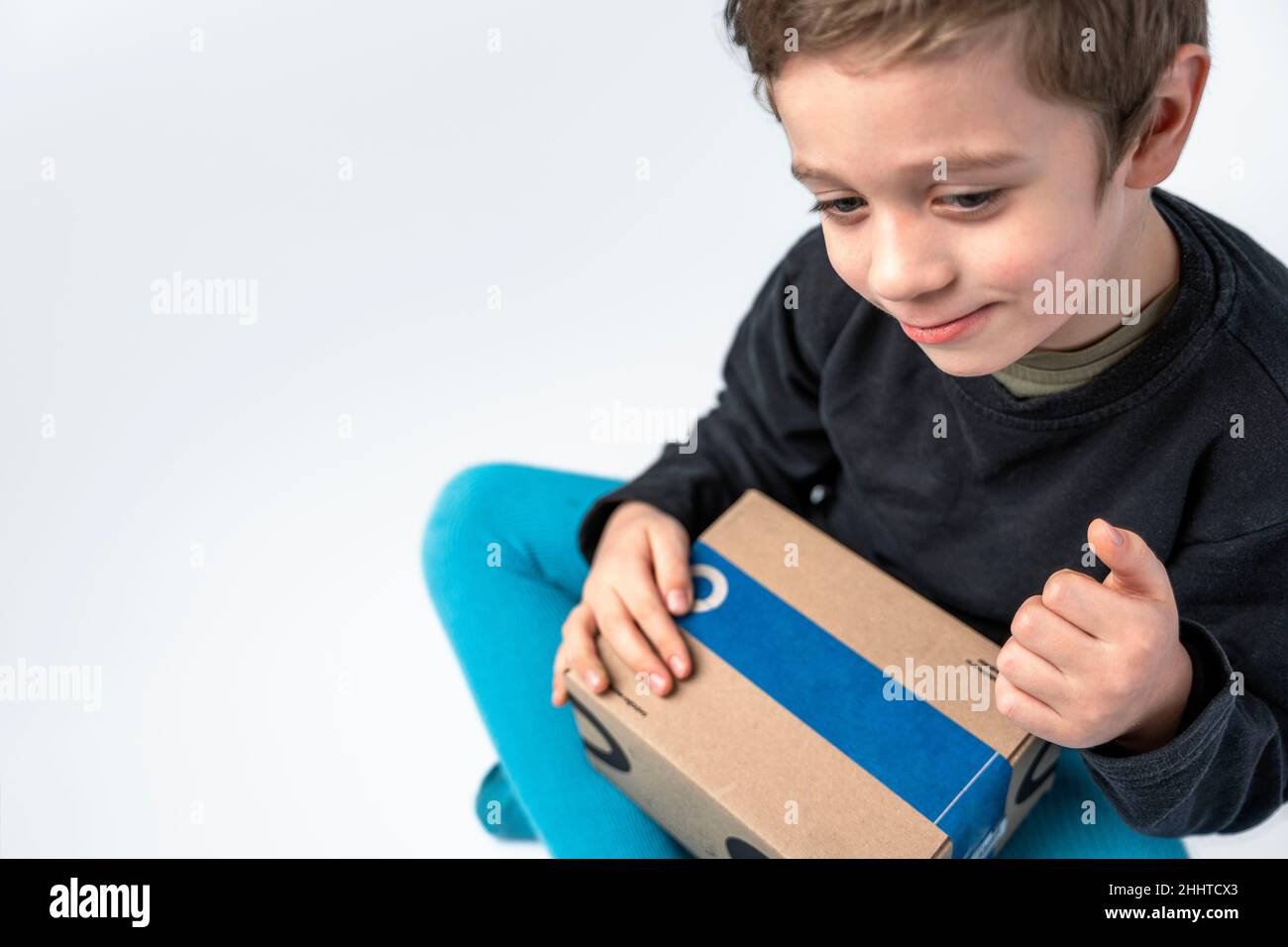 The child holds a cardboard box with a gift sent by the delivery ...