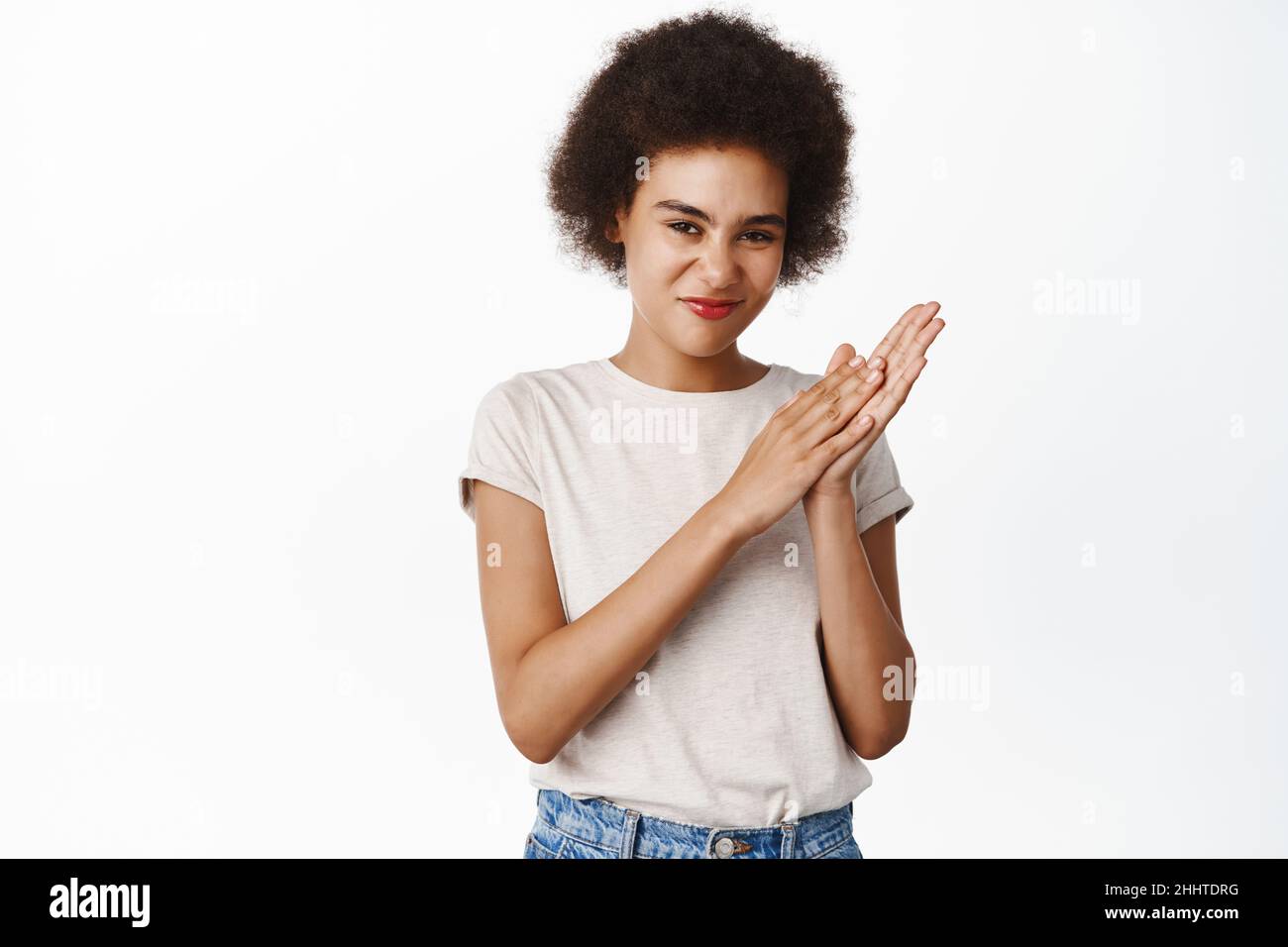 Image of smiling coy african girl rubbing hands and smiling, making ...