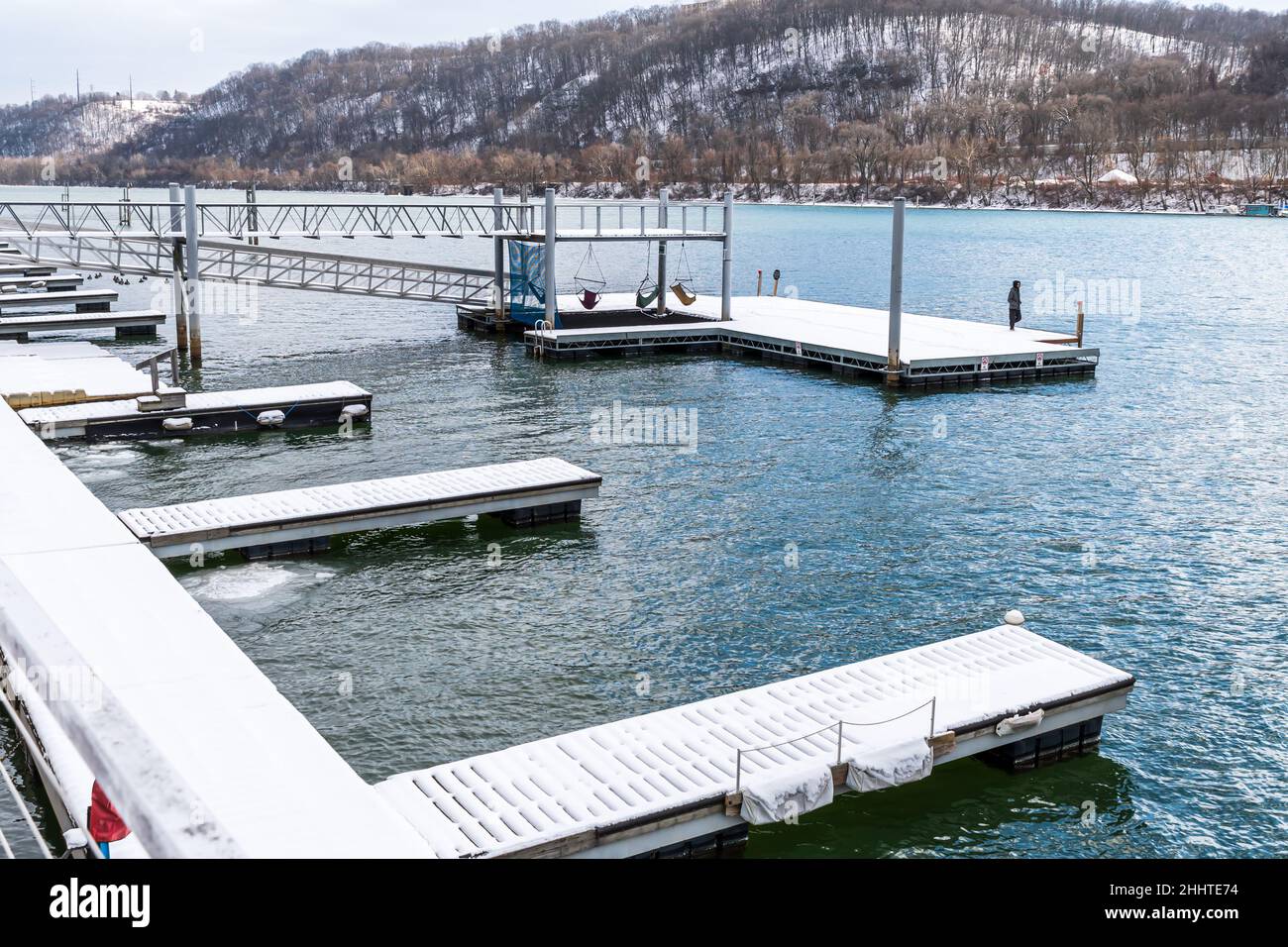 A man walking on a snow covered empty boat dock on the Allegheny River ...