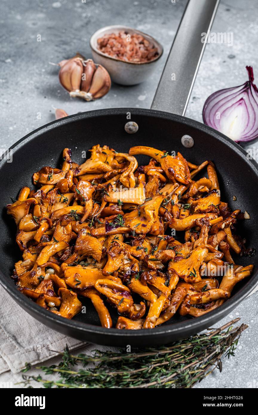 Fried chanterelle mushrooms with onions and thyme in a skillet. Gray ...