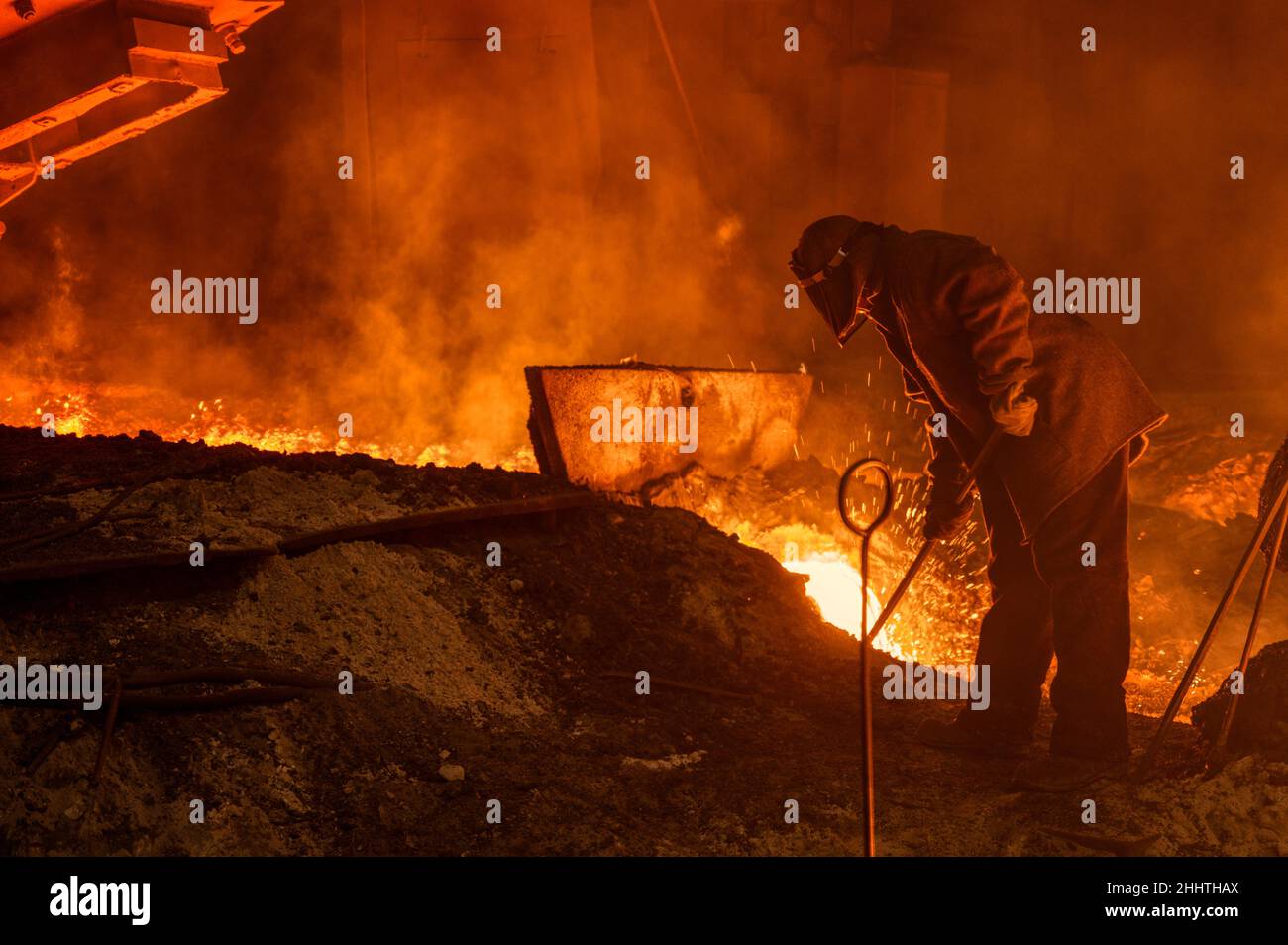 The process of releasing pig iron from a blast furnace. A man works ...
