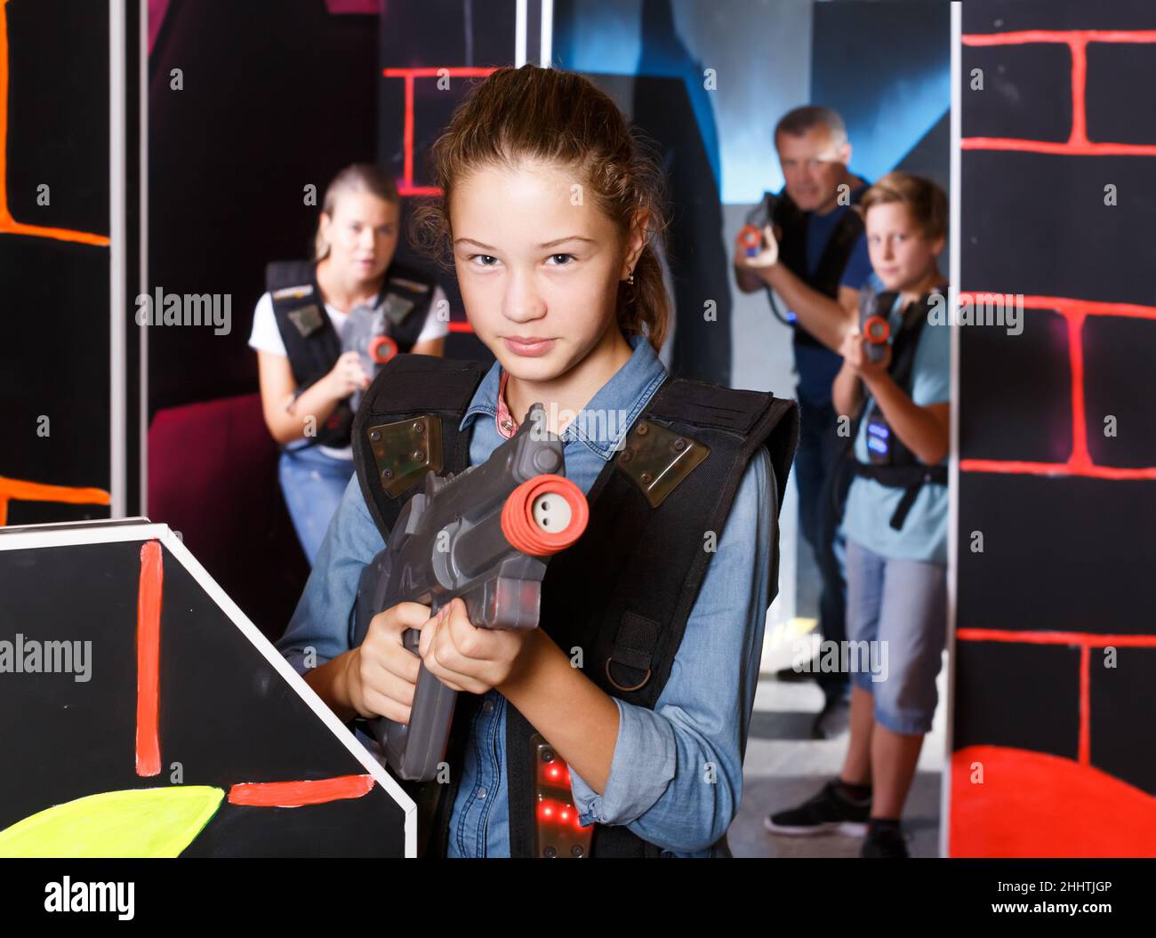 Excited girl aiming laser gun at other players Stock Photo - Alamy