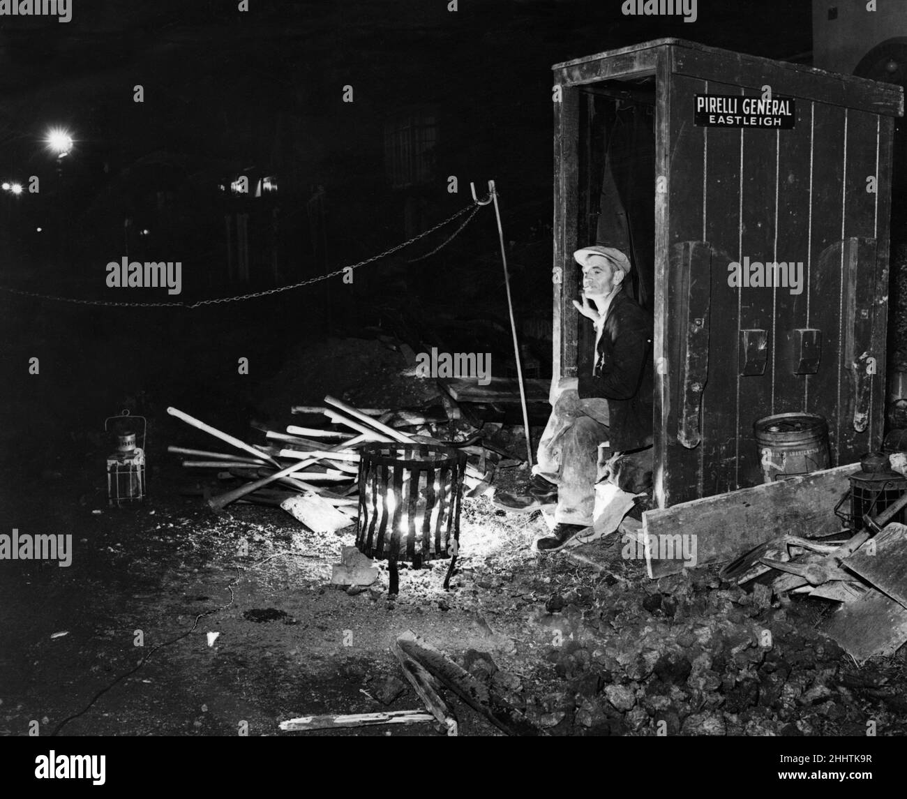 Night Watchman keeps himself warm by a brazier whilst guarding road ...