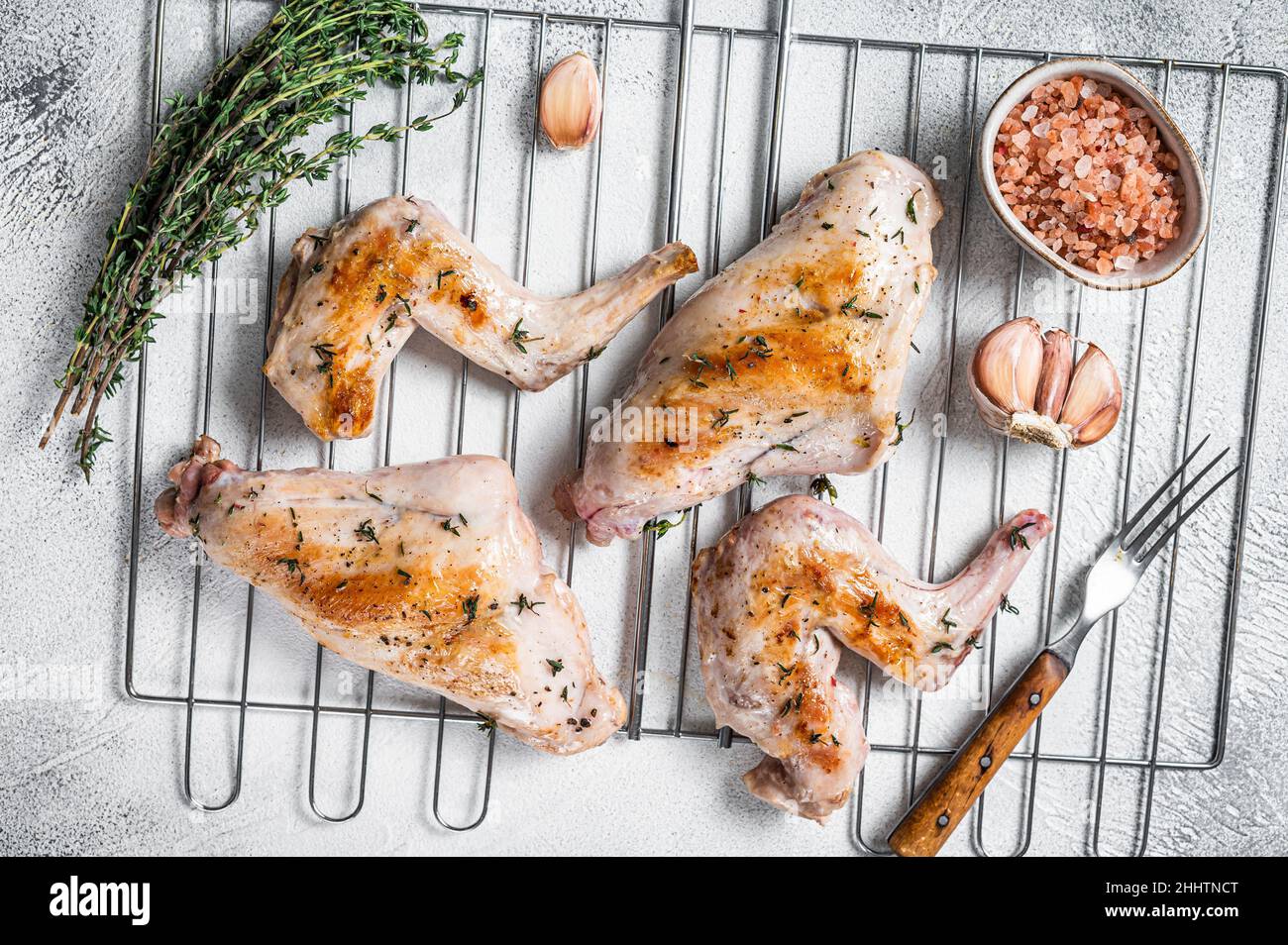 Baked rabbit legs on a grill with thyme. White background. Top view ...