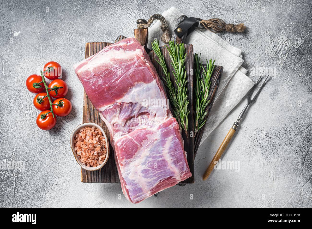 Pork belly block, raw meat with skin on a wooden board with rosemary ...