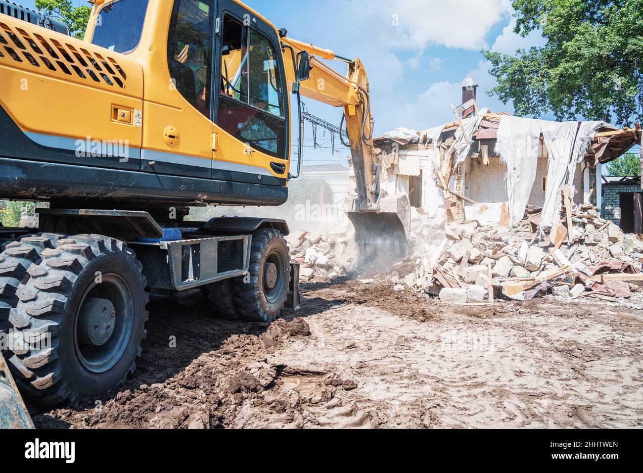 Yellow excavator or bulldozer destroys building. Building demolition ...