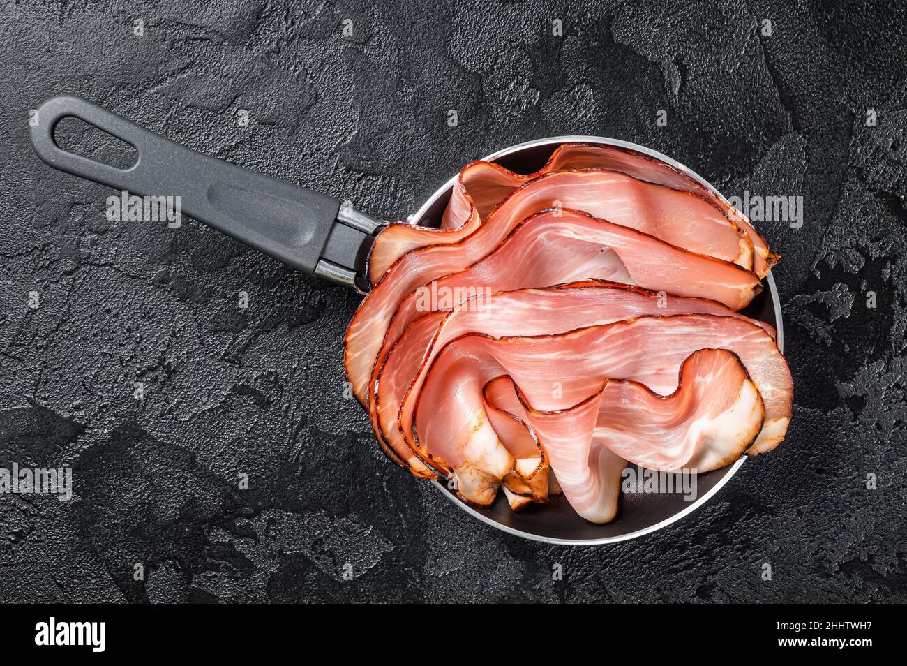 Cooking of Black Forest Ham in skillet. Black background. Top view ...