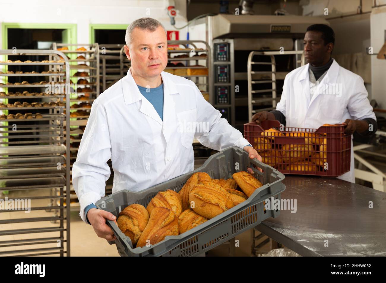 Two bakers arranging baked bread in bakery Stock Photo - Alamy
