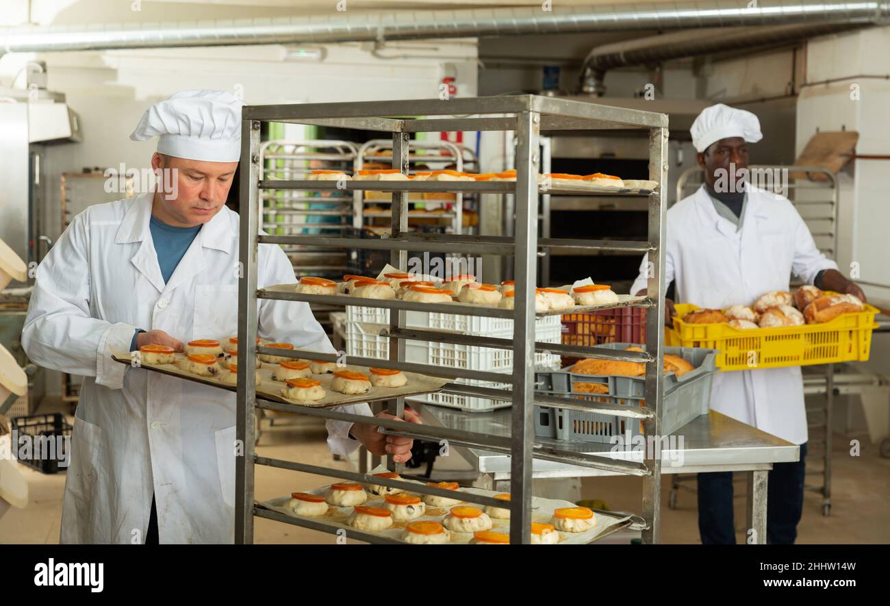 Baker pushing trolley with baked bread Stock Photo - Alamy