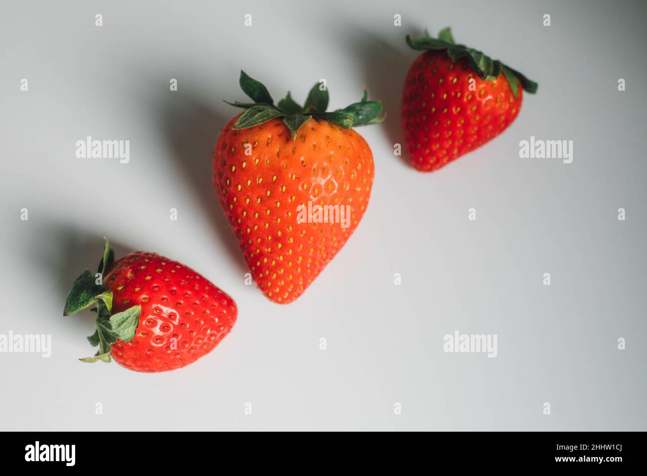 three strawberries on white background Stock Photo - Alamy