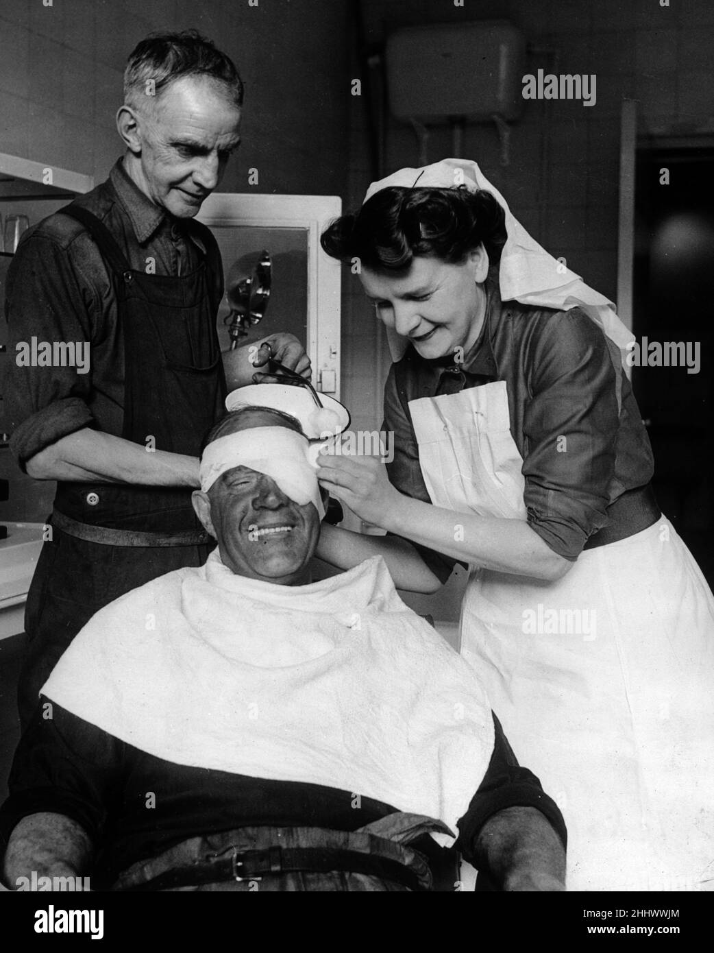 Sister Eira Davies, with help from ambulance man John Price, removes a ...