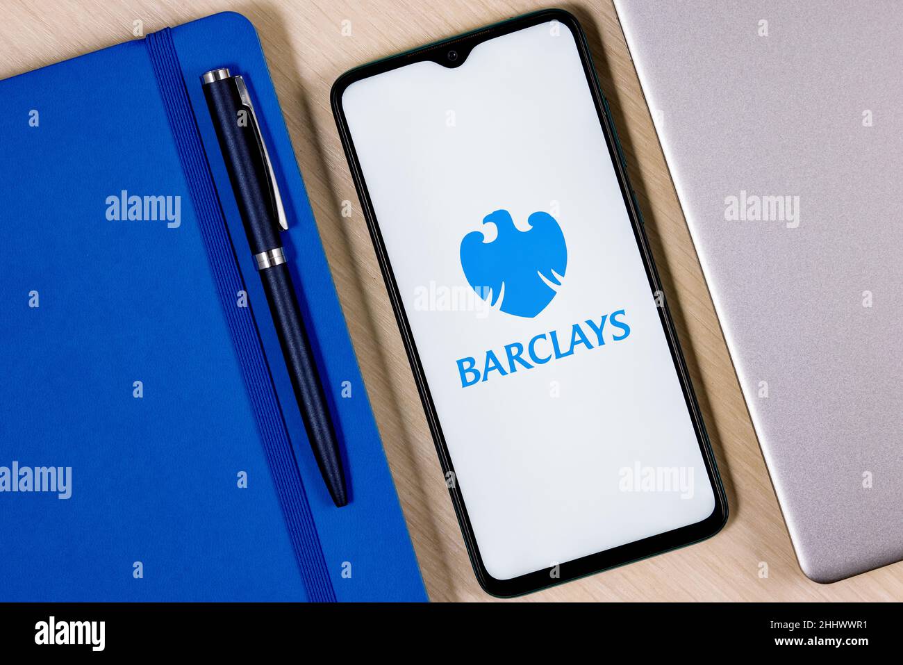 Smartphone with Barclays bank logo on wooden table next to laptop and ...