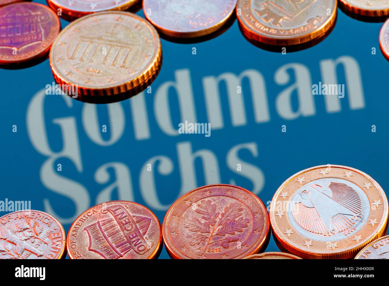 Variety of metal coins on background of Goldman Sachs bank logo Stock ...