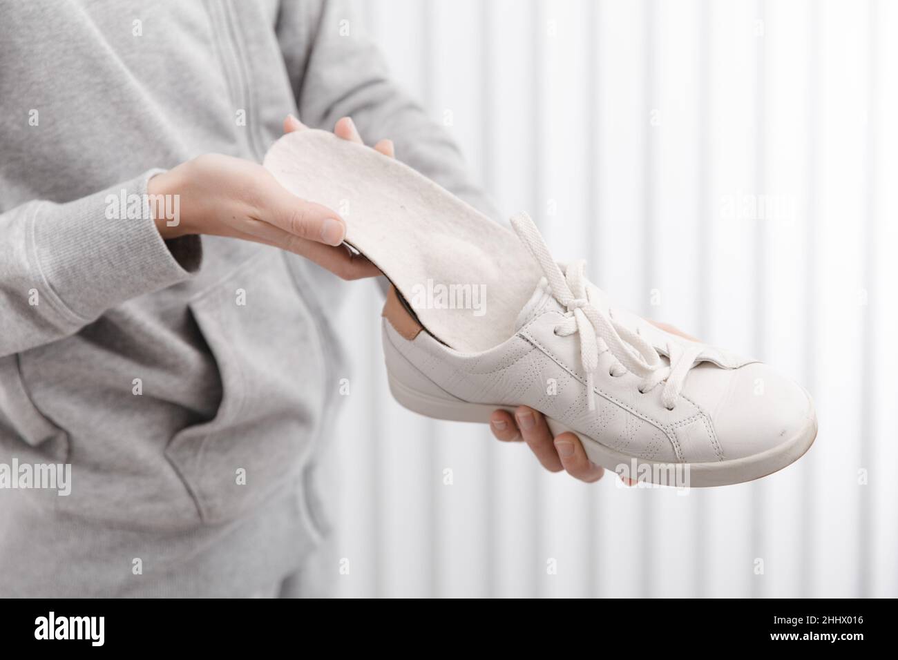 Woman putting orthopedic insole into shoe at home. Sports girl fitting ...