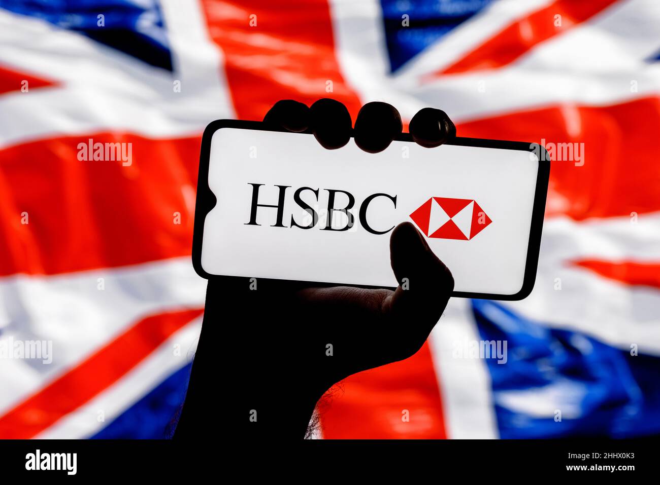 Smartphone with HSBC bank logo in clenched hand on background of ...