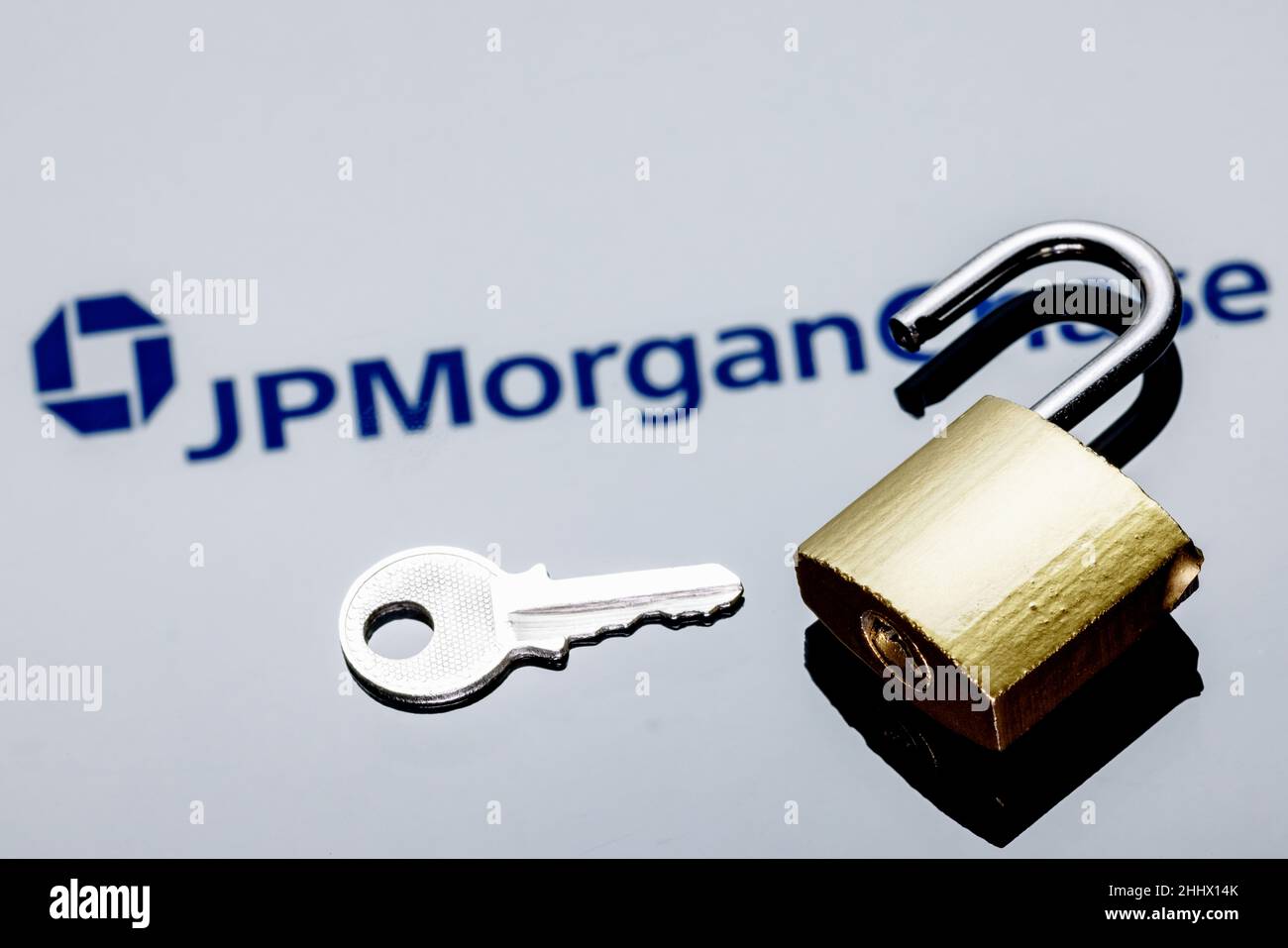 An open security lock and key on background of JPMorgan Chase bank logo ...