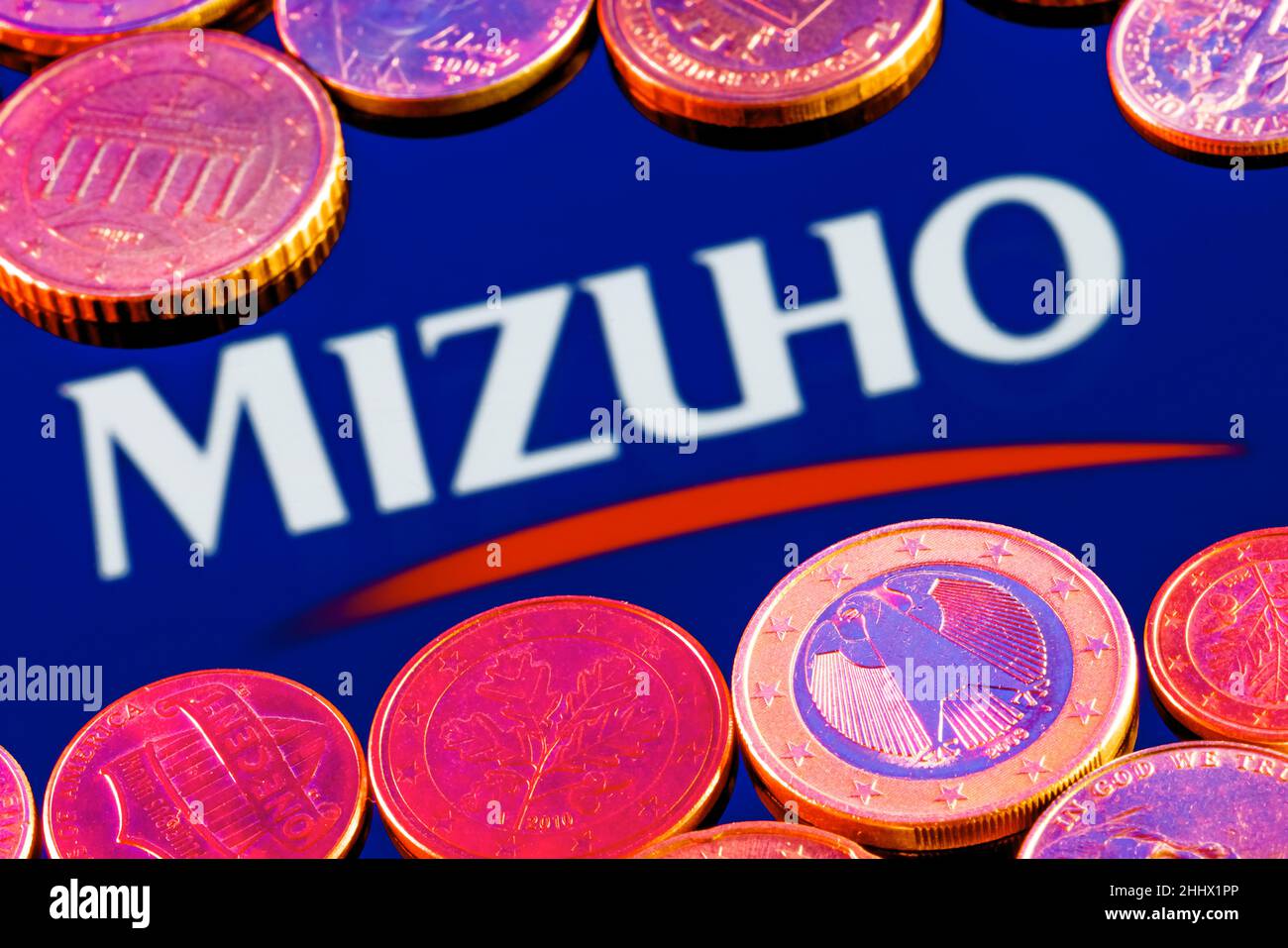 Variety of metal coins on background of Mizuho Financial Group logo ...