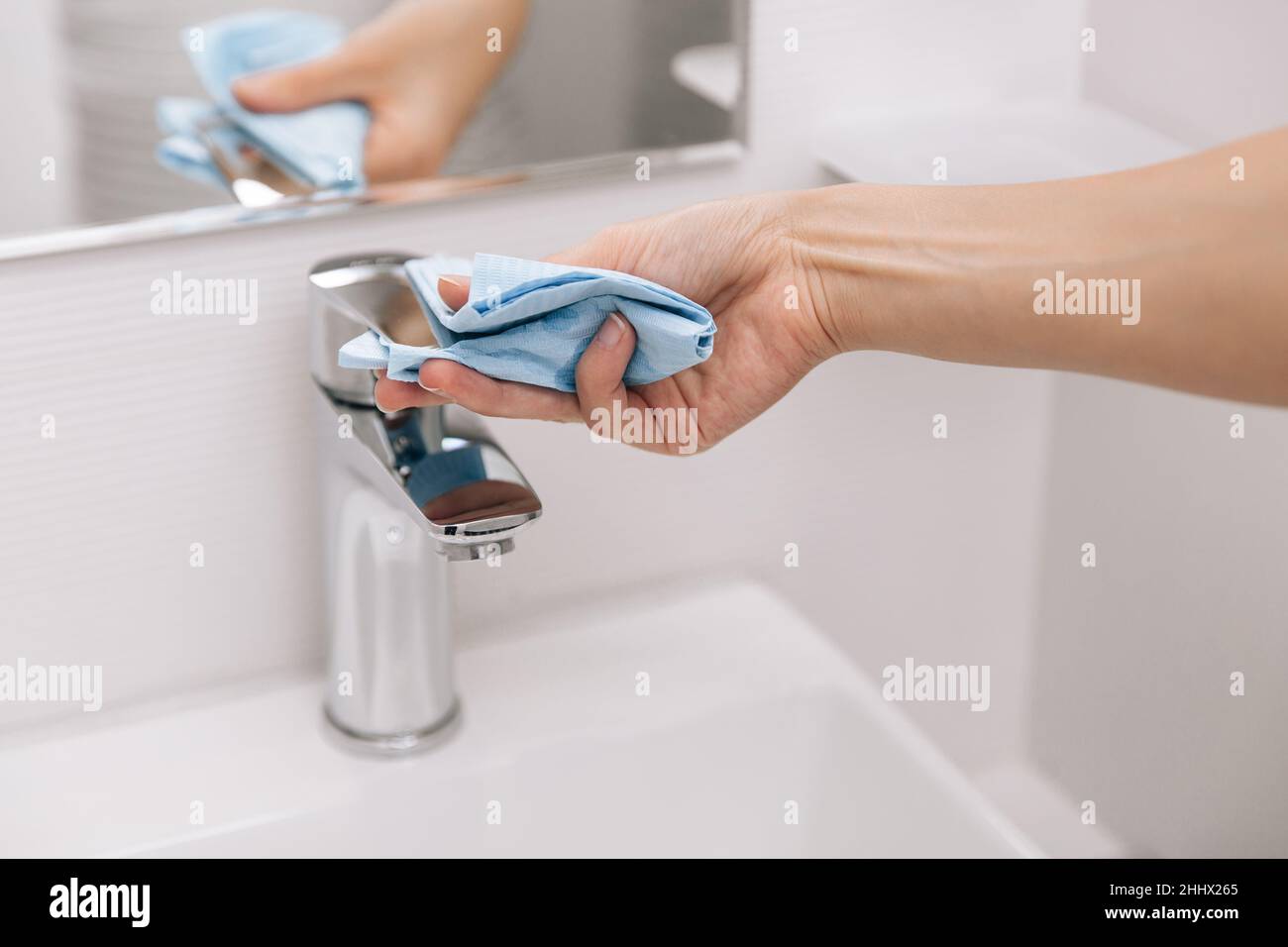 Cleaning the sink faucet with a microfiber cloth. Sanitize surfaces ...