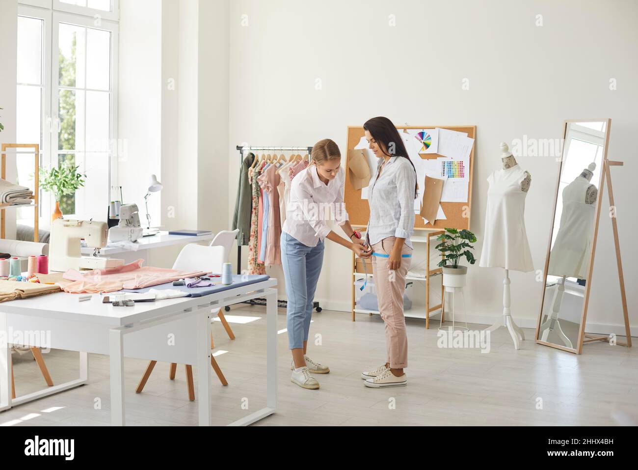 Seamstress in sewing workshop takes measurements of client to sew ...