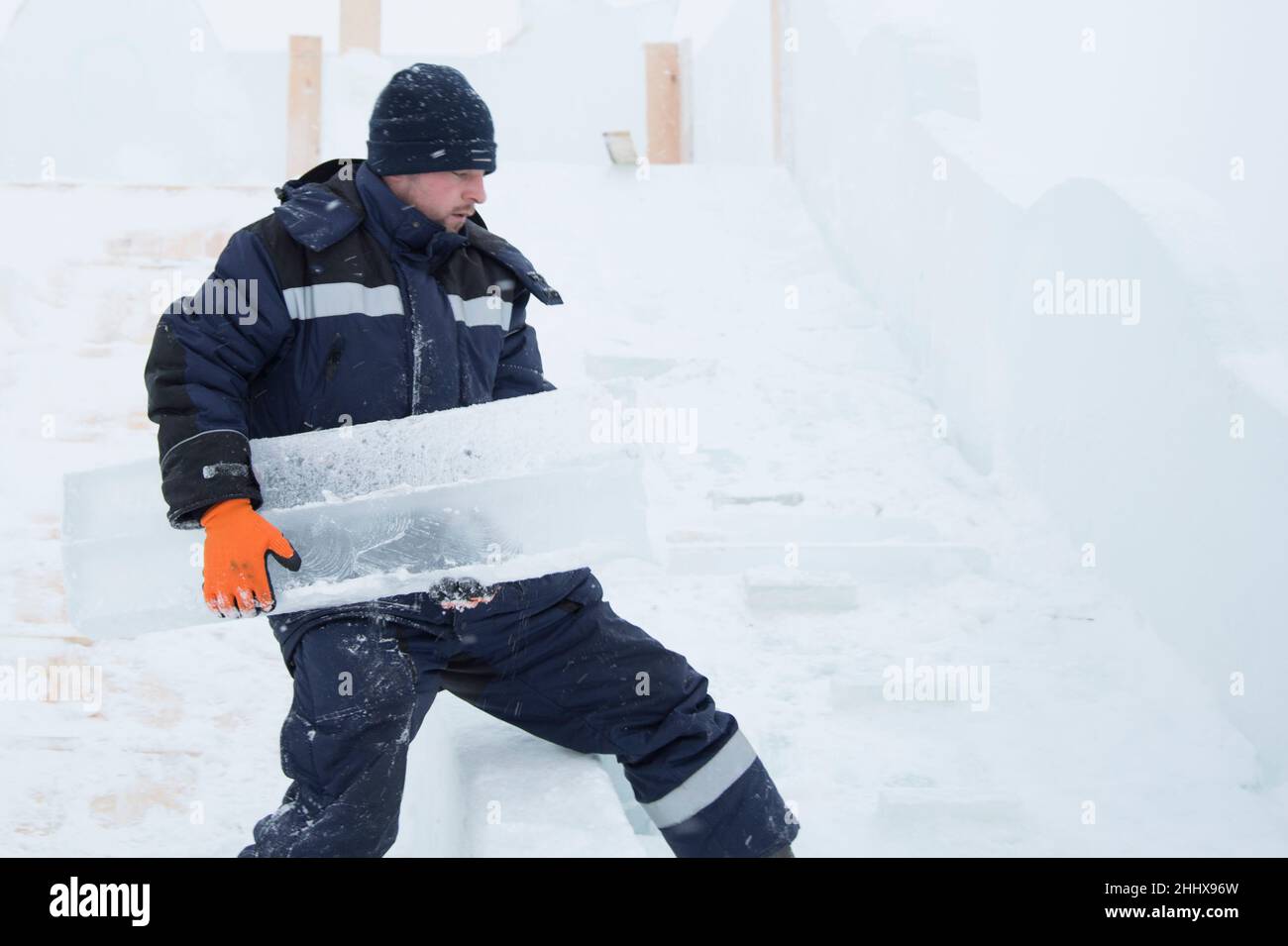 A worker carries an ice block in his arms along the assembly site of ...