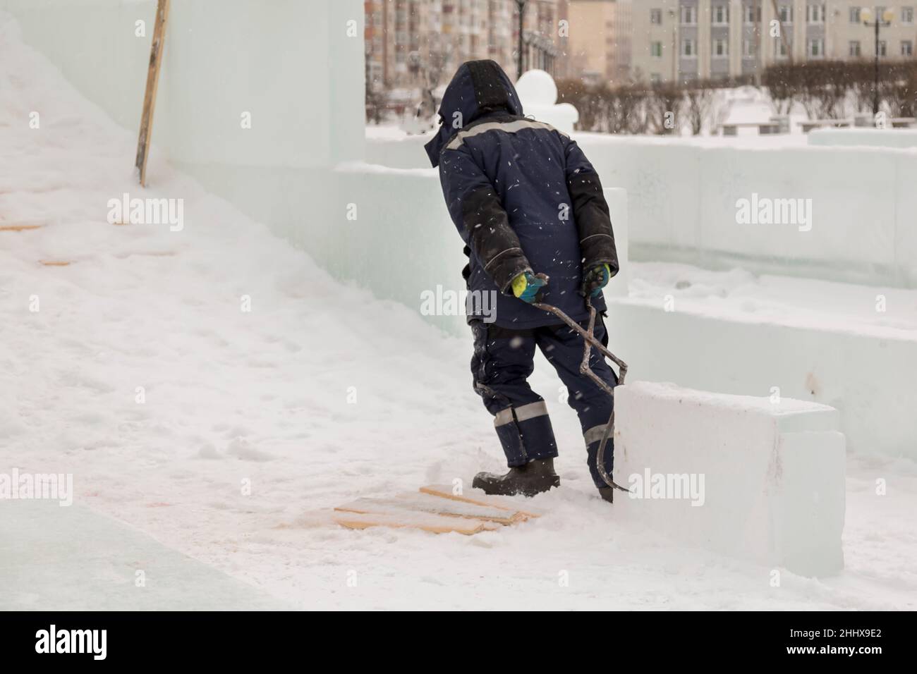 The worker pulls the ice block around the ice camp assembly site with ...