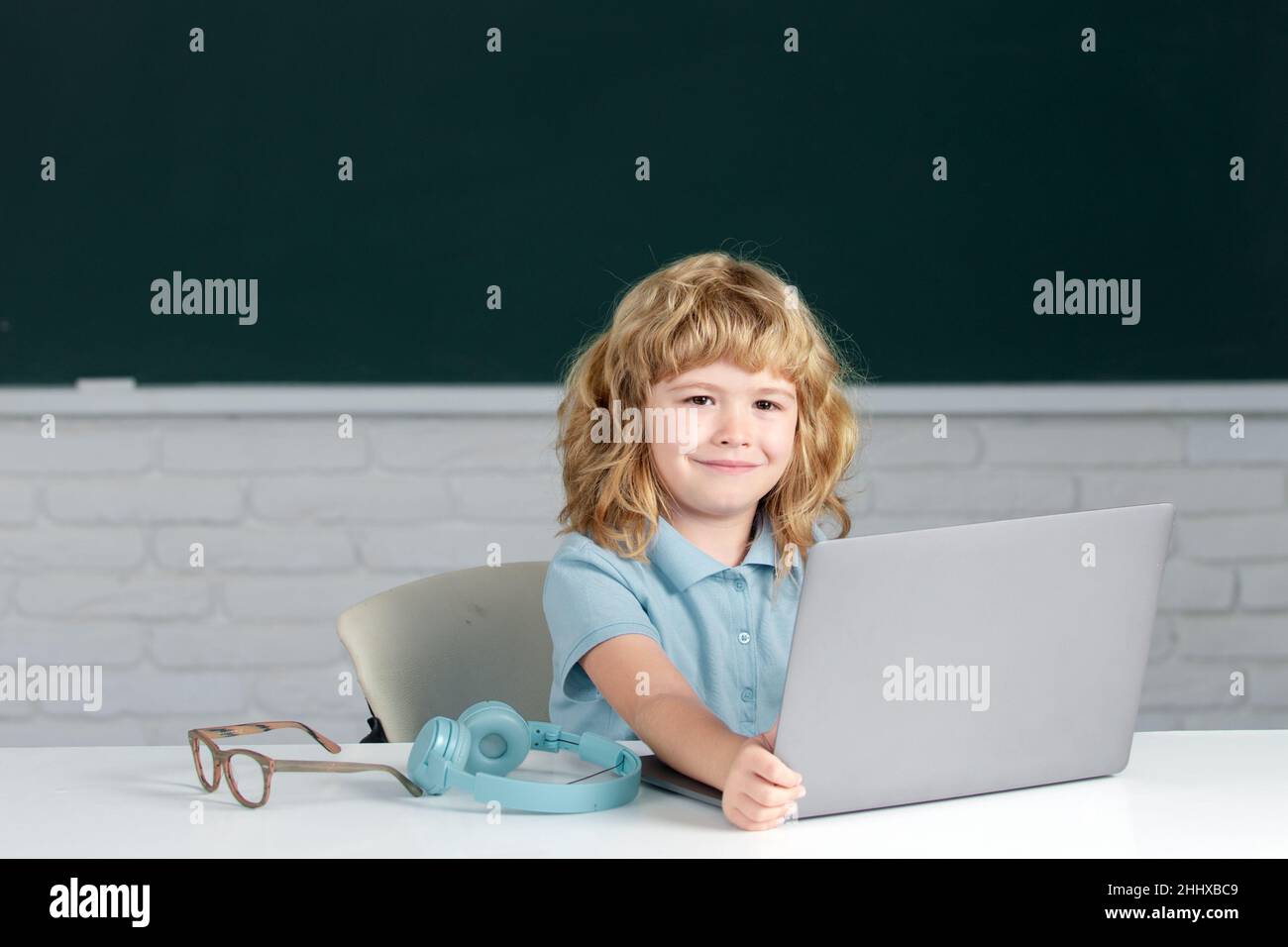 Little smiling student boy using laptop computer in school class Stock ...