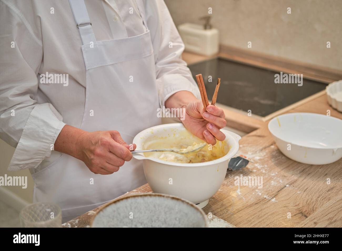An adult woman in white chef clothes cooking pie in a beige kitchen ...