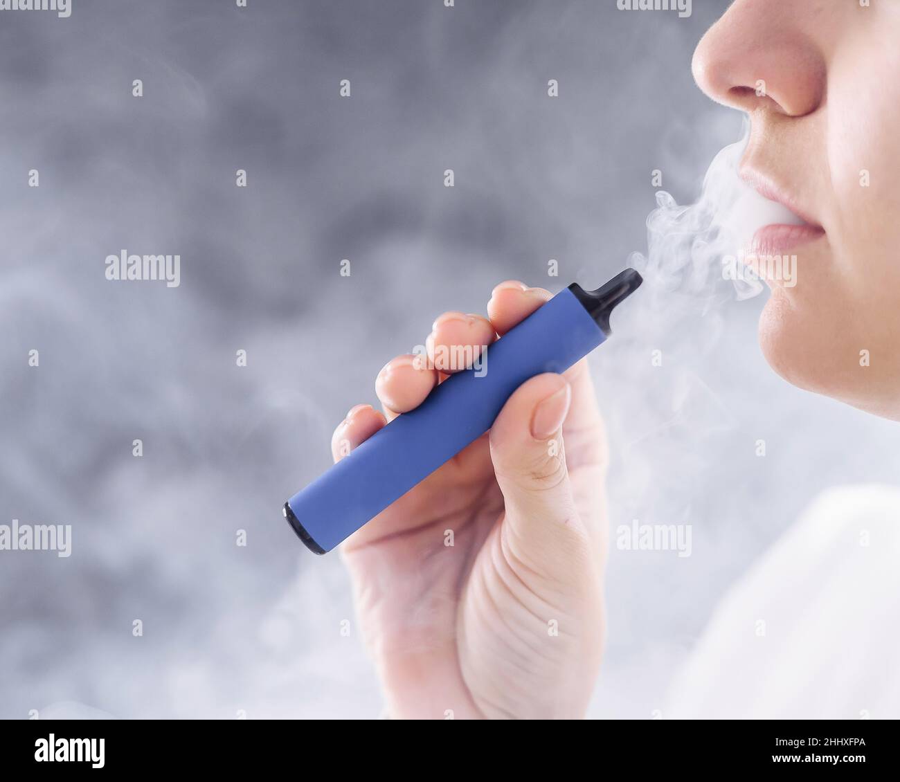 Caucasian woman smokes a disposable vape in the studio Stock Photo - Alamy
