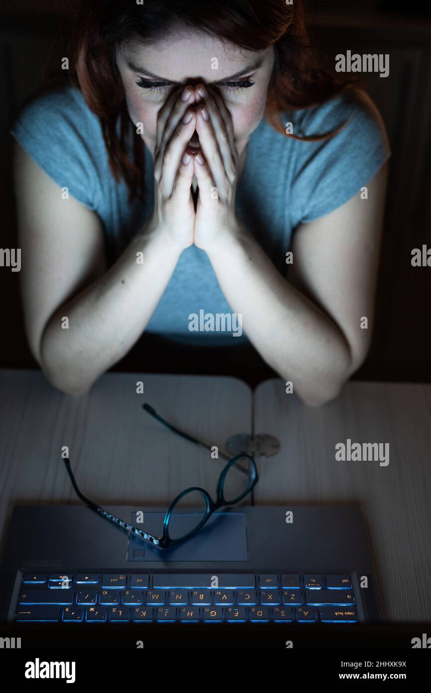woman works overtime. A student studying at a laptop at night in the ...