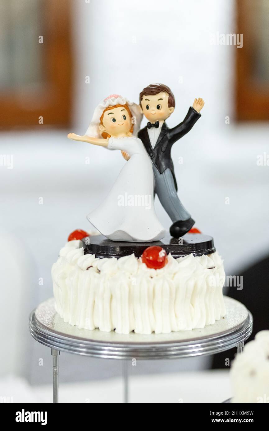 A vertical shot of a simple cute wedding cake with a couple statues ...