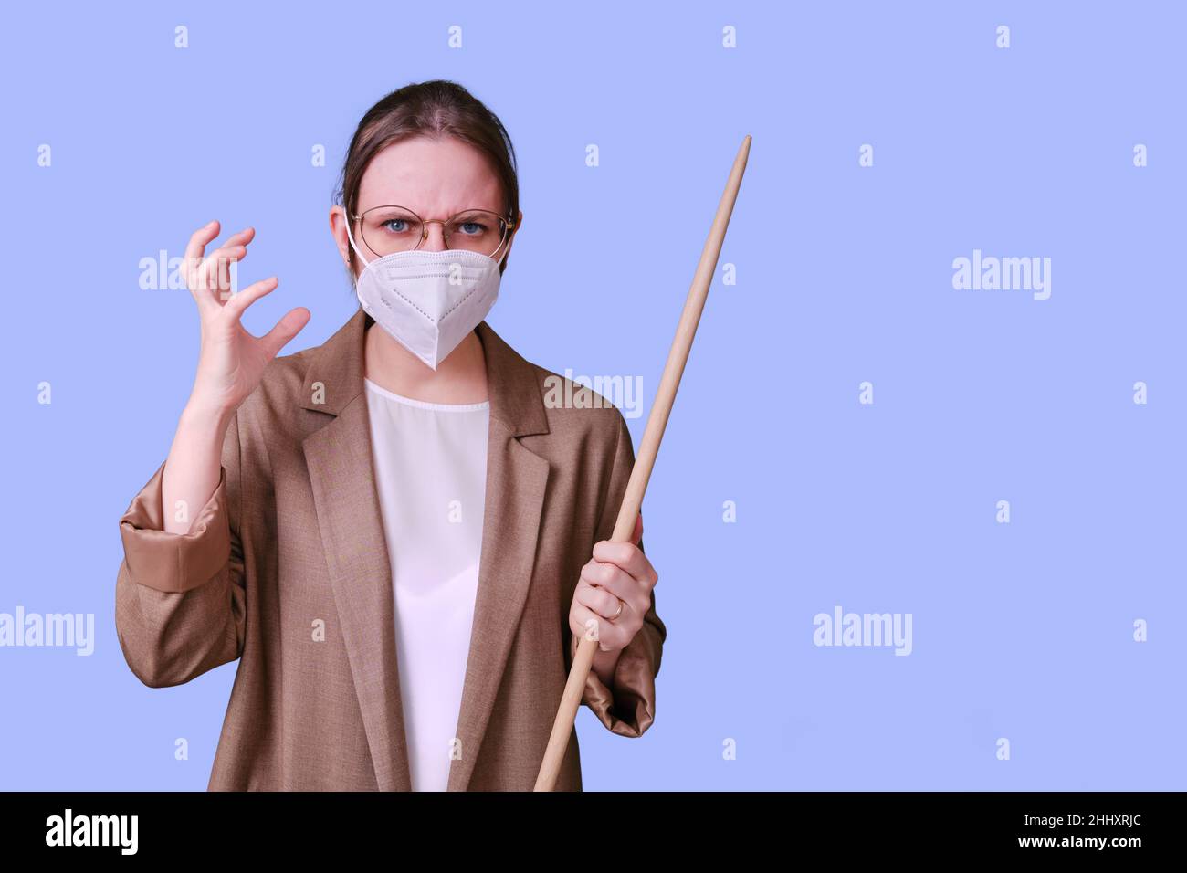 Angry woman teacher in medical face mask on studio purple background ...