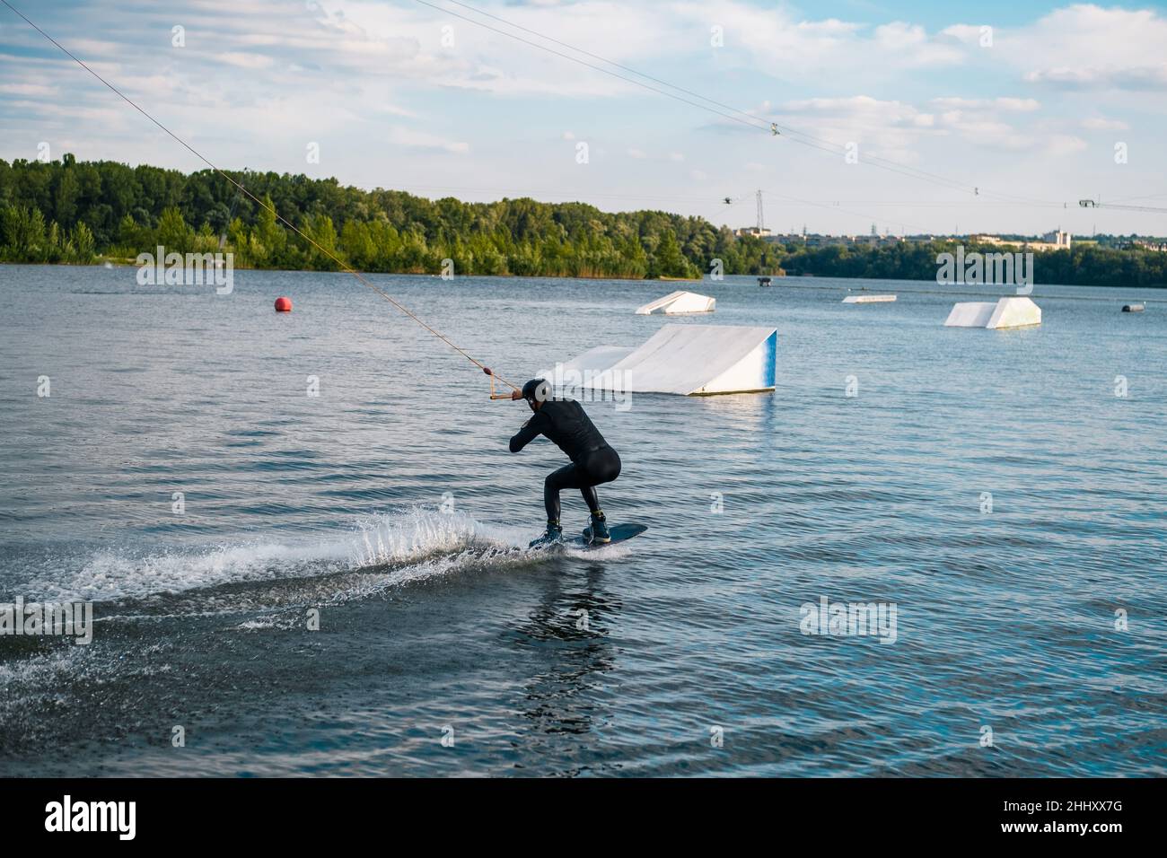 Wakeboarder sliding on water on board getting ready to perform ramp ...
